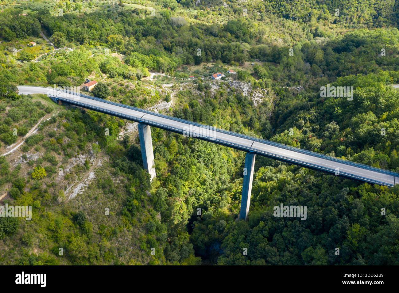 Aerial view of a sleek elevated bridge crossing a deep, forested gorge ...