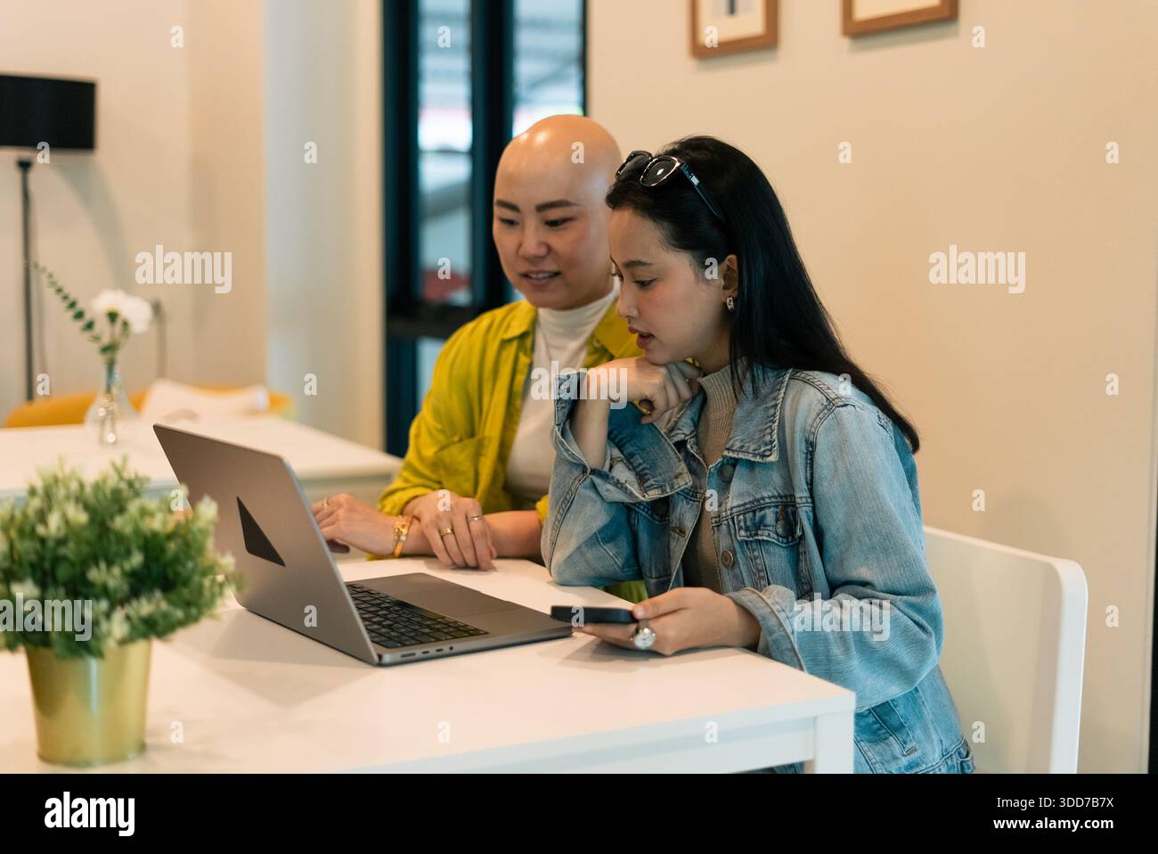Two women collaborating on laptop, working and learning together at a ...