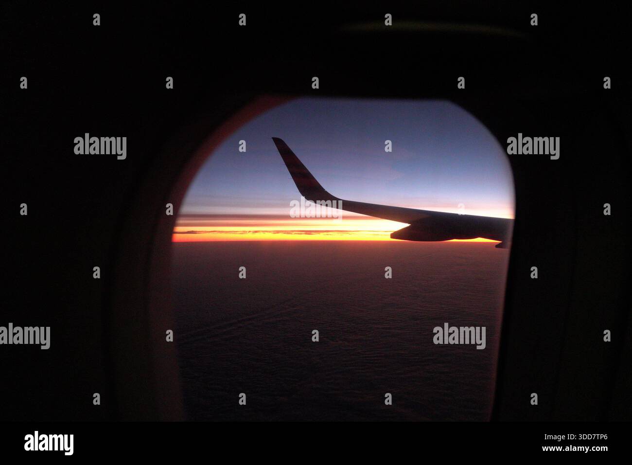 A warm glow is seen on the horizon from air airplane window as sthe ...