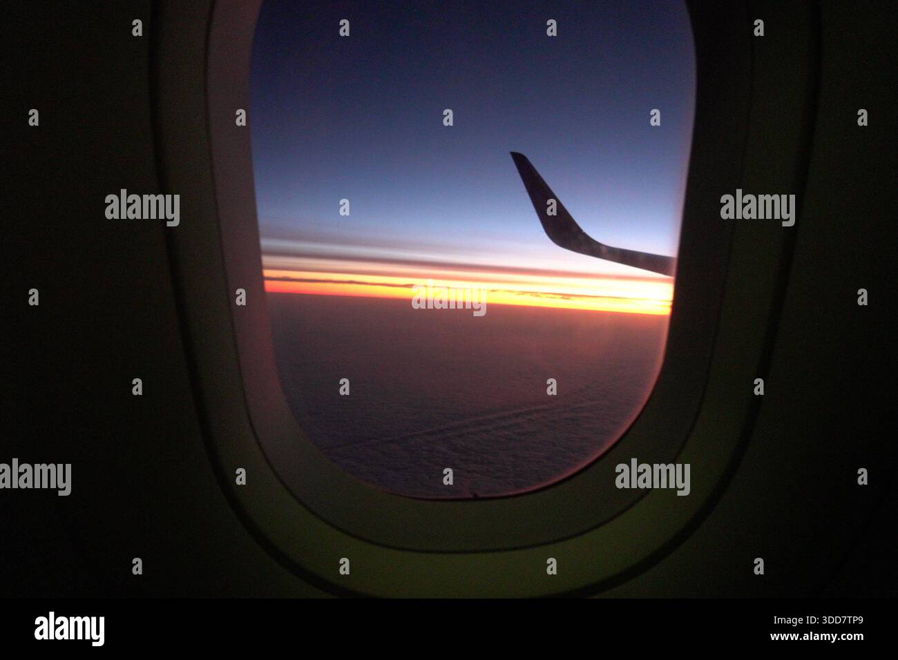 A warm glow is seen on the horizon from air airplane window as sthe ...