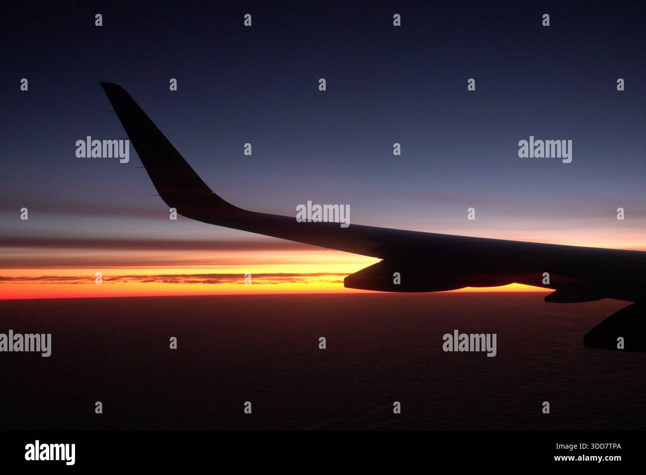 A warm glow is seen on the horizon from air airplane window as sthe ...