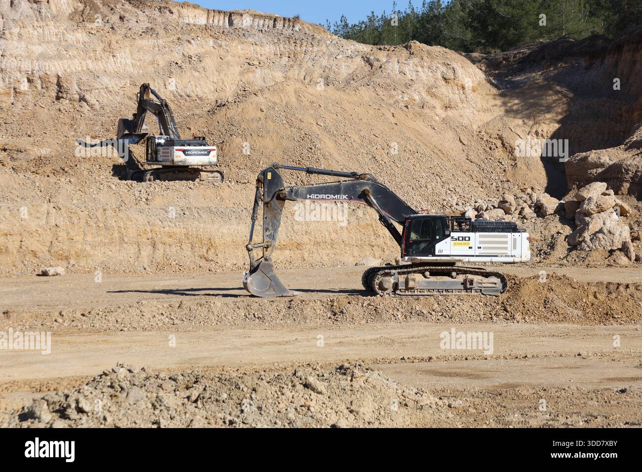 Heavy excavators extracting fill material from a quarry for road ...