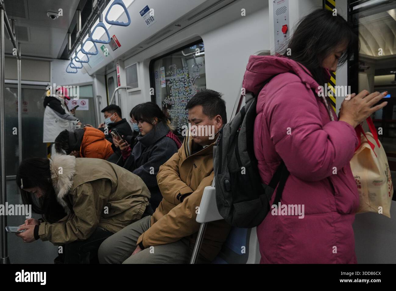 People browse on their smartphones as they ride a subway train during ...