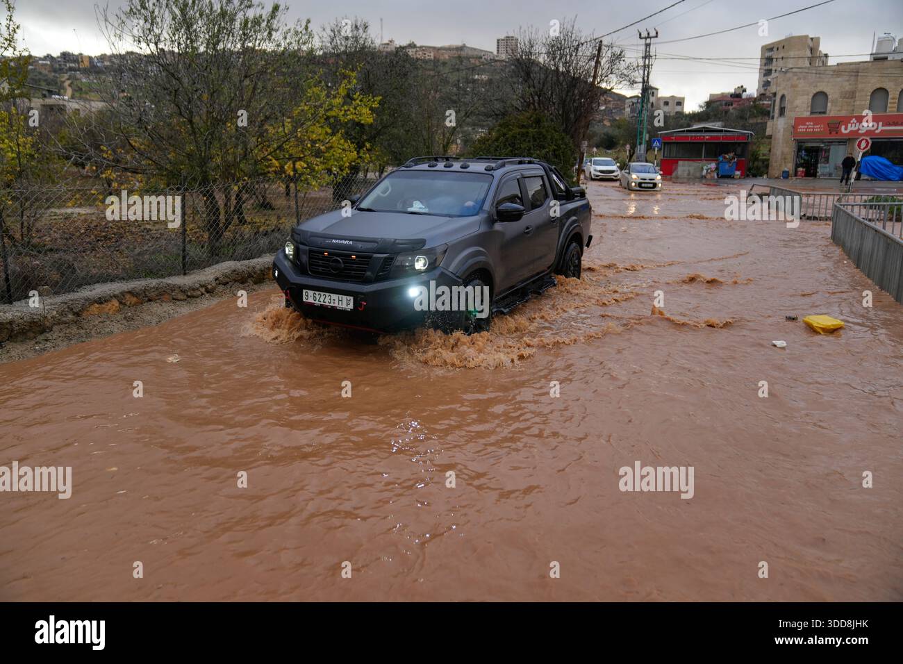 Palestinian motorists drive through a rain flooded street during a ...