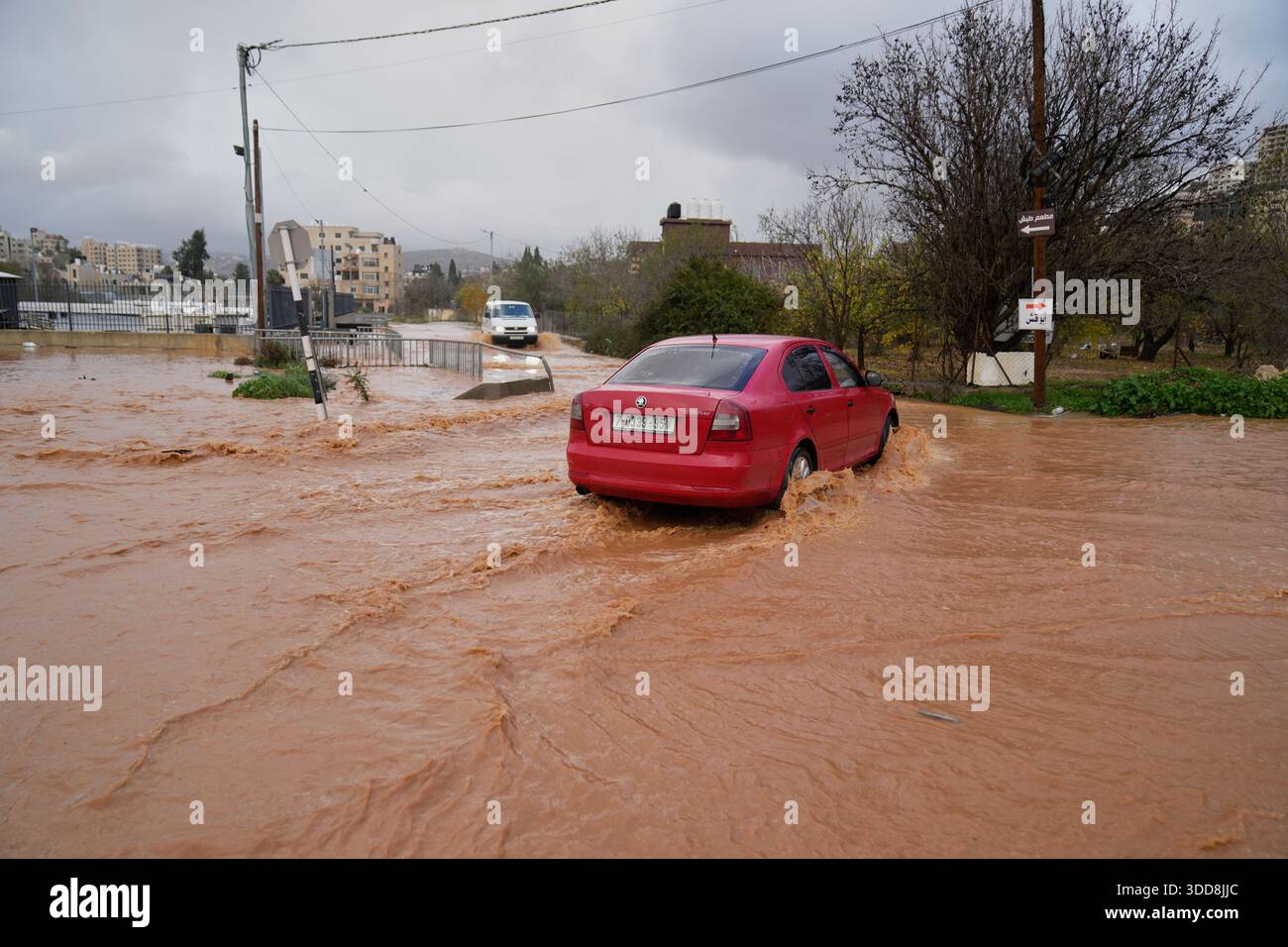 Palestinian motorists drive through a rain flooded street during a ...