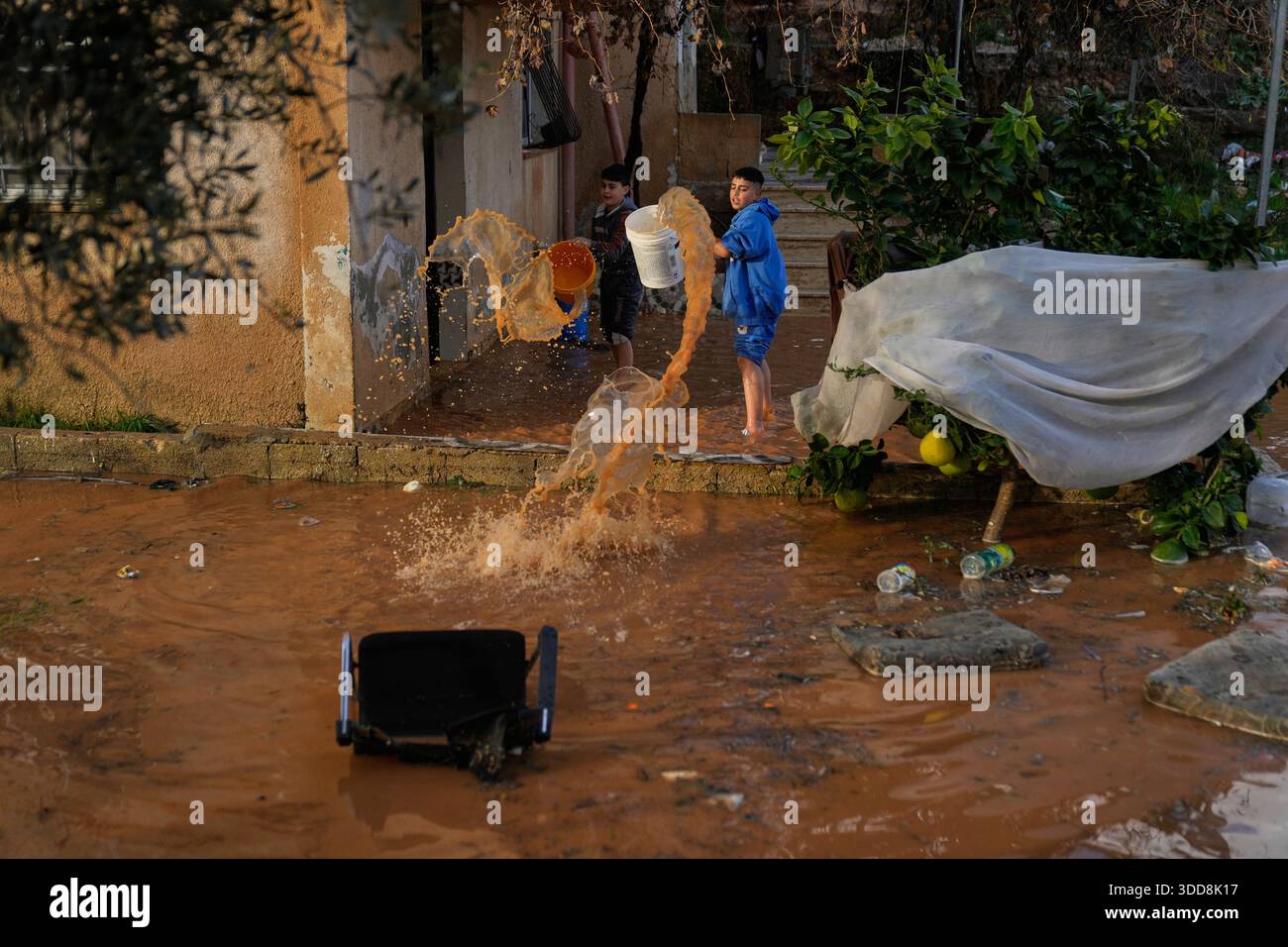 Palestinian youths clear their rain flooded houses during a powerful ...