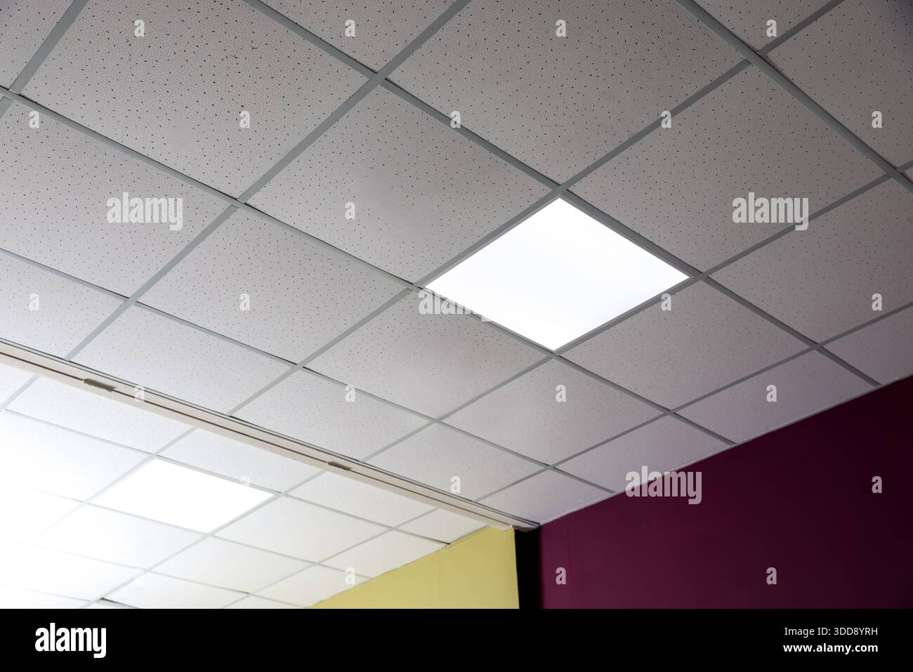 Tiled ceiling with lighting and cctv camera indoors, low angle view ...