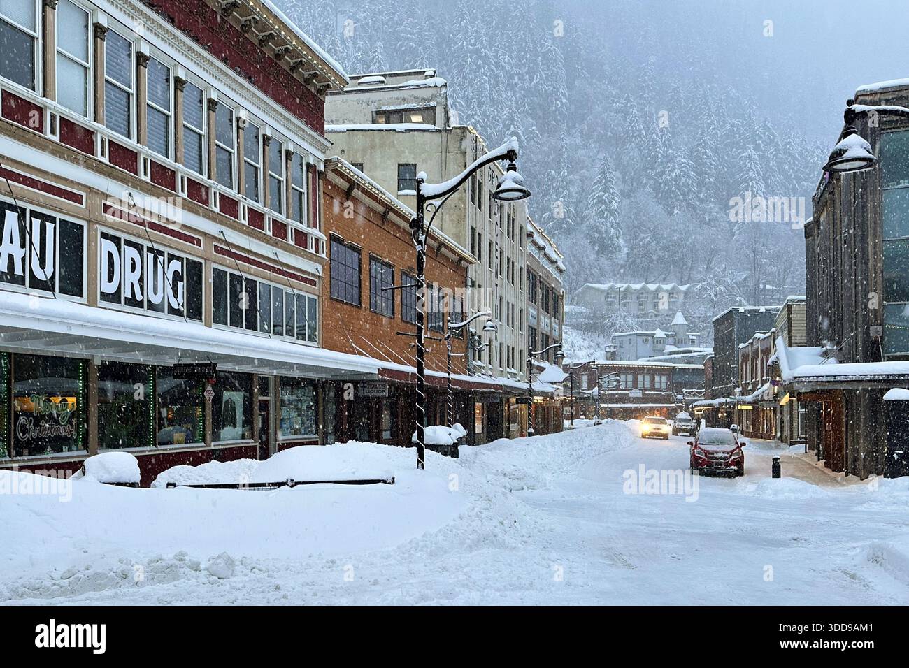 A car drives down a snowy main street in downtown Juneau, Alaska ...