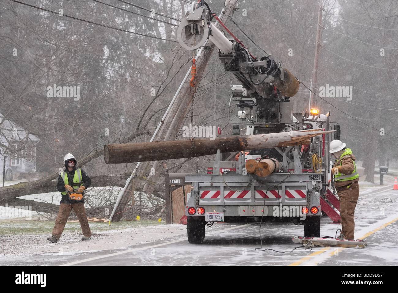 Utility crew workers replace a power pole snapped in two when high ...