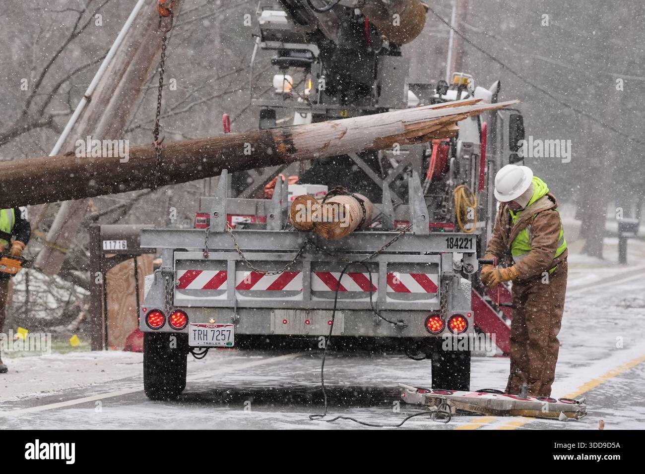 Utility crew workers replace a power pole snapped in two when high ...