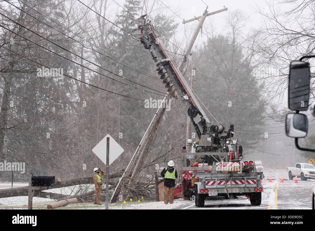 Utility crew workers replace a power pole snapped in two when high ...