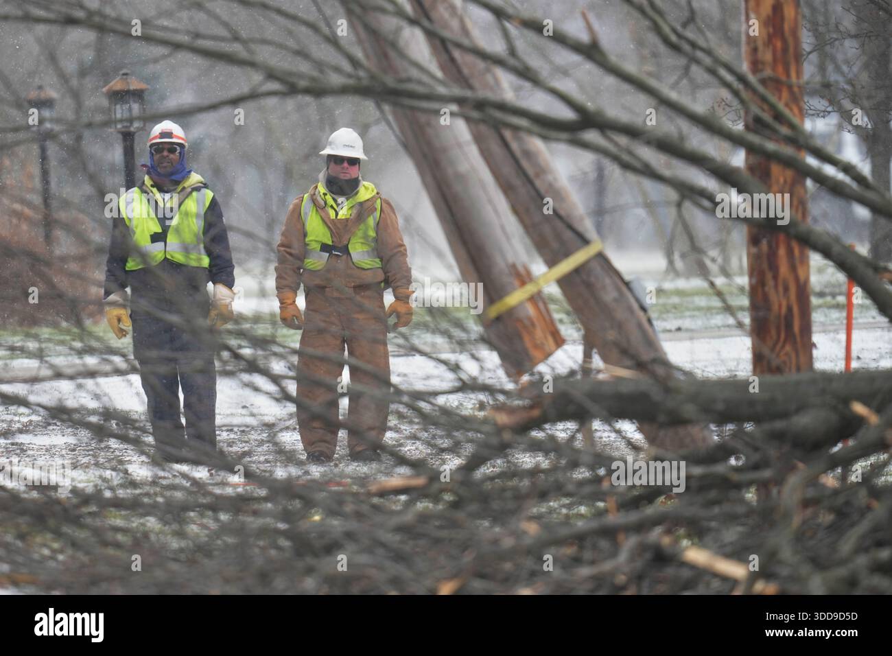 Utility crew workers replace a power pole snapped in two when high ...