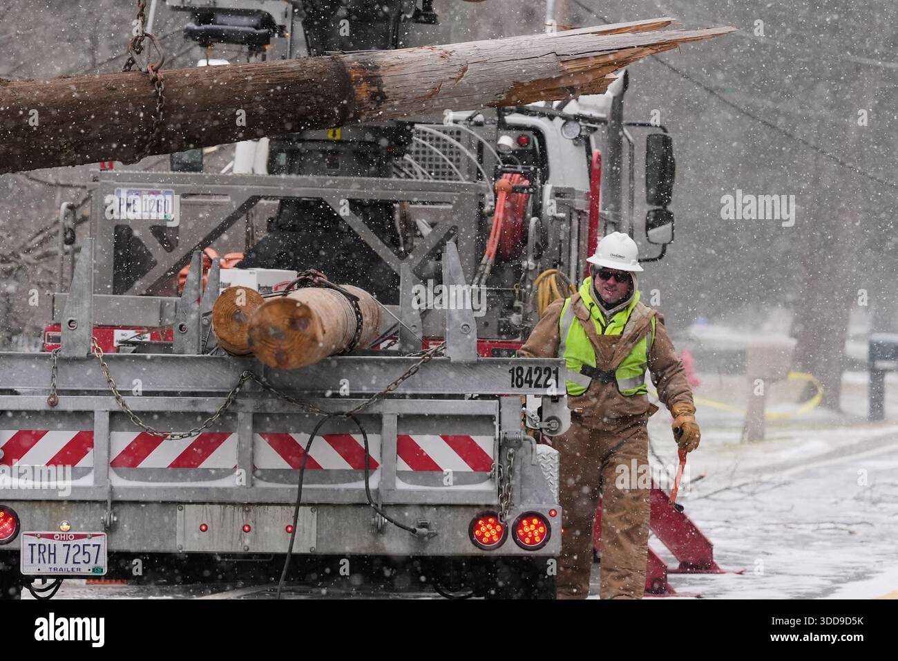 Utility crew workers replace a power pole snapped in two when high ...