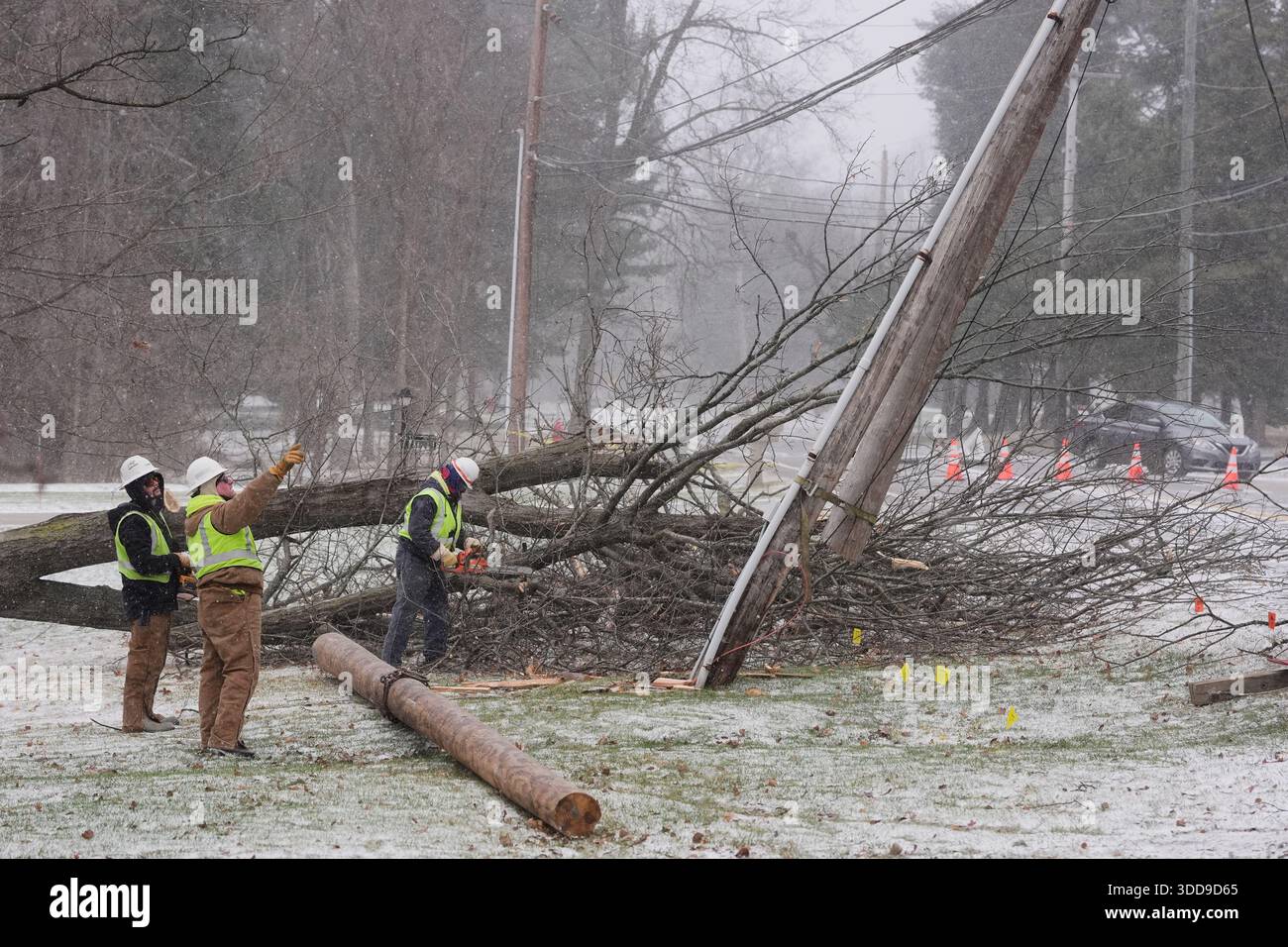Utility crew workers replace a power pole snapped in two when high ...