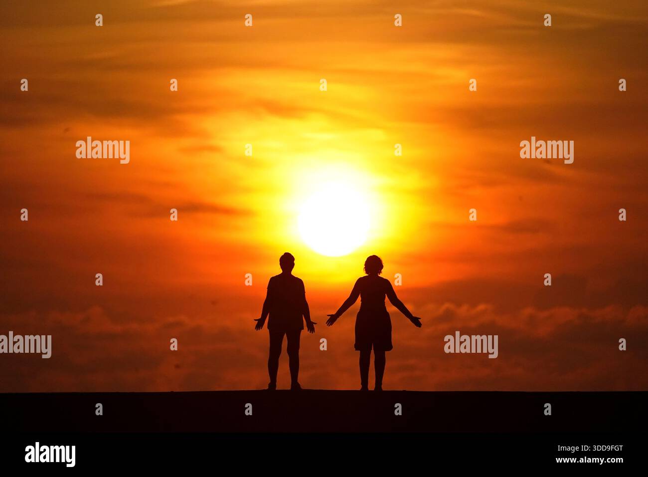 FILE - A couple stands on a jetty as the sun rises over the Atlantic ...