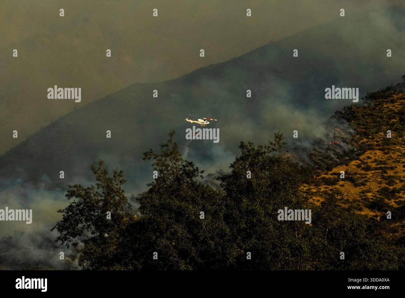 A helicopter flies over a wildfire on the Precordillera of the Andes in ...