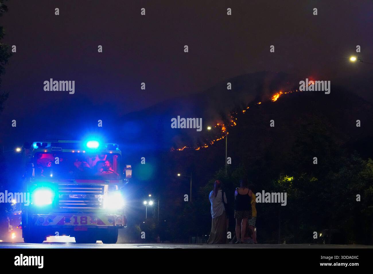A family looks out at a wildfire on the Precordillera of the Andes in ...