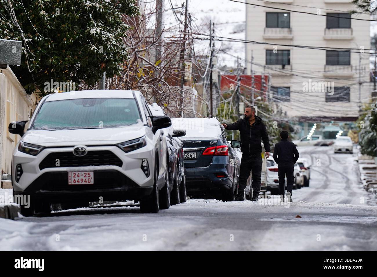 An Iraqi Kurdish man clears snow from his car as snow covers in the ...