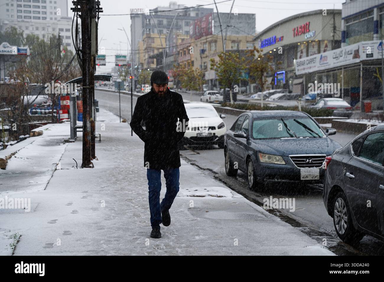 An Iraqi Kurdish man walks along a street as snow covers in the city of ...