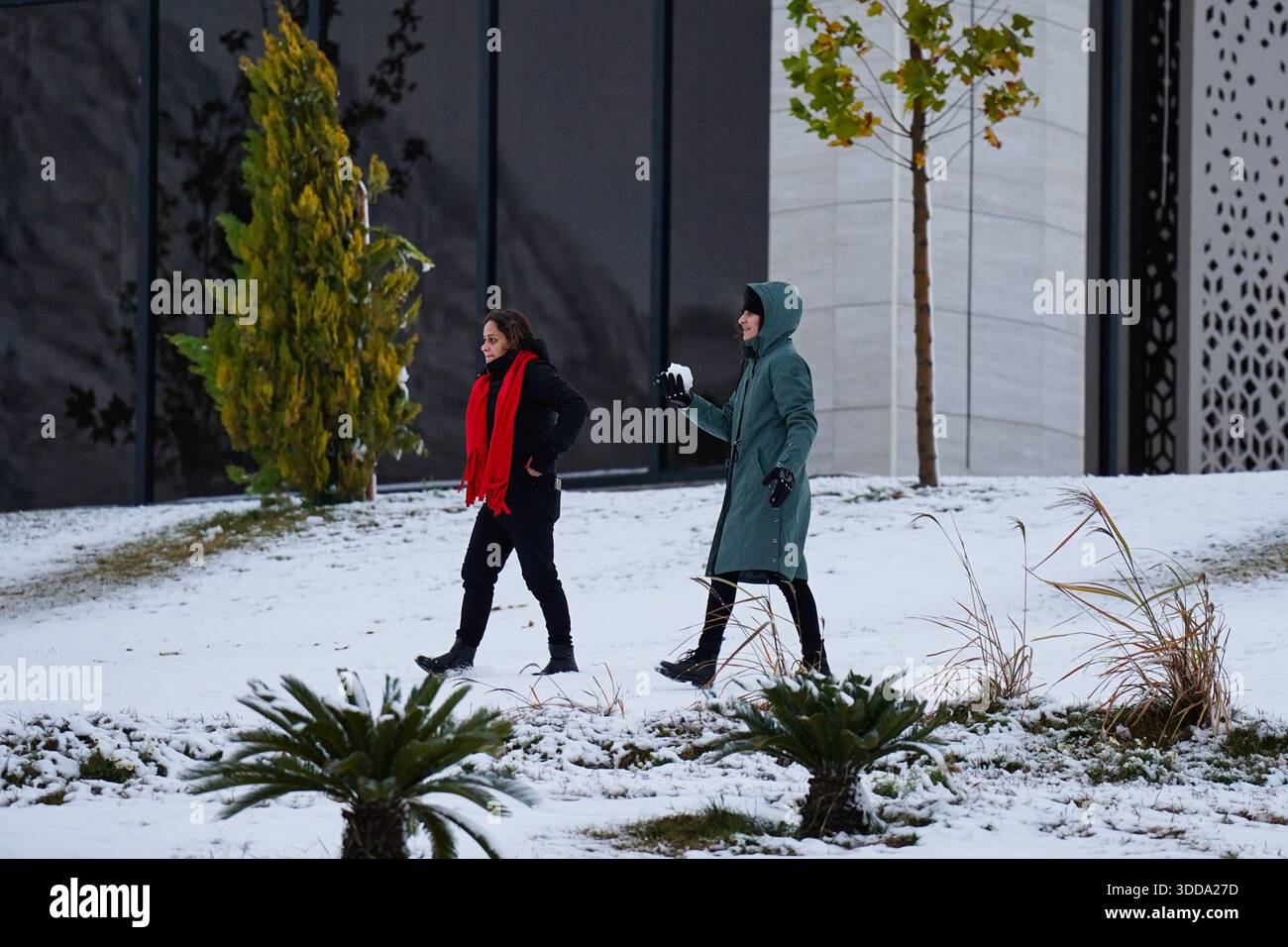 Iraqi Kurdish women walk along a park as snow covers in the city of ...
