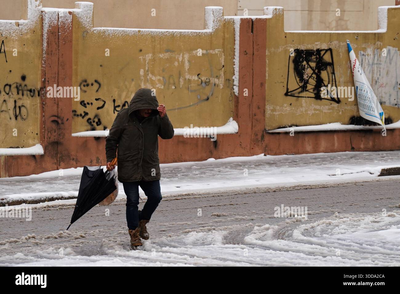 An Iraqi Kurdish man walks along a street as snow covers in the city of ...