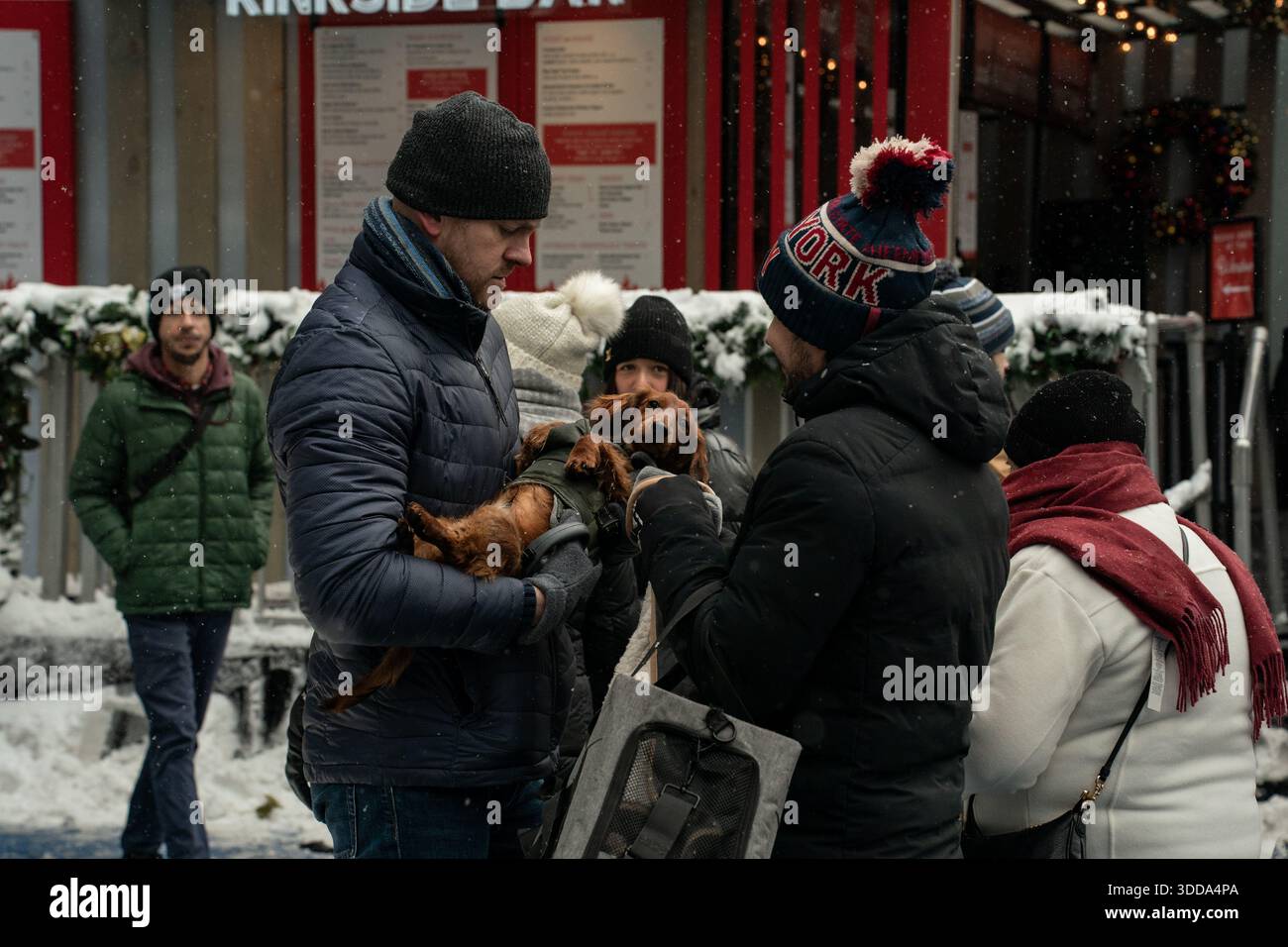 Two men clean the paws of their dog at the Bryant Park Holiday Market ...