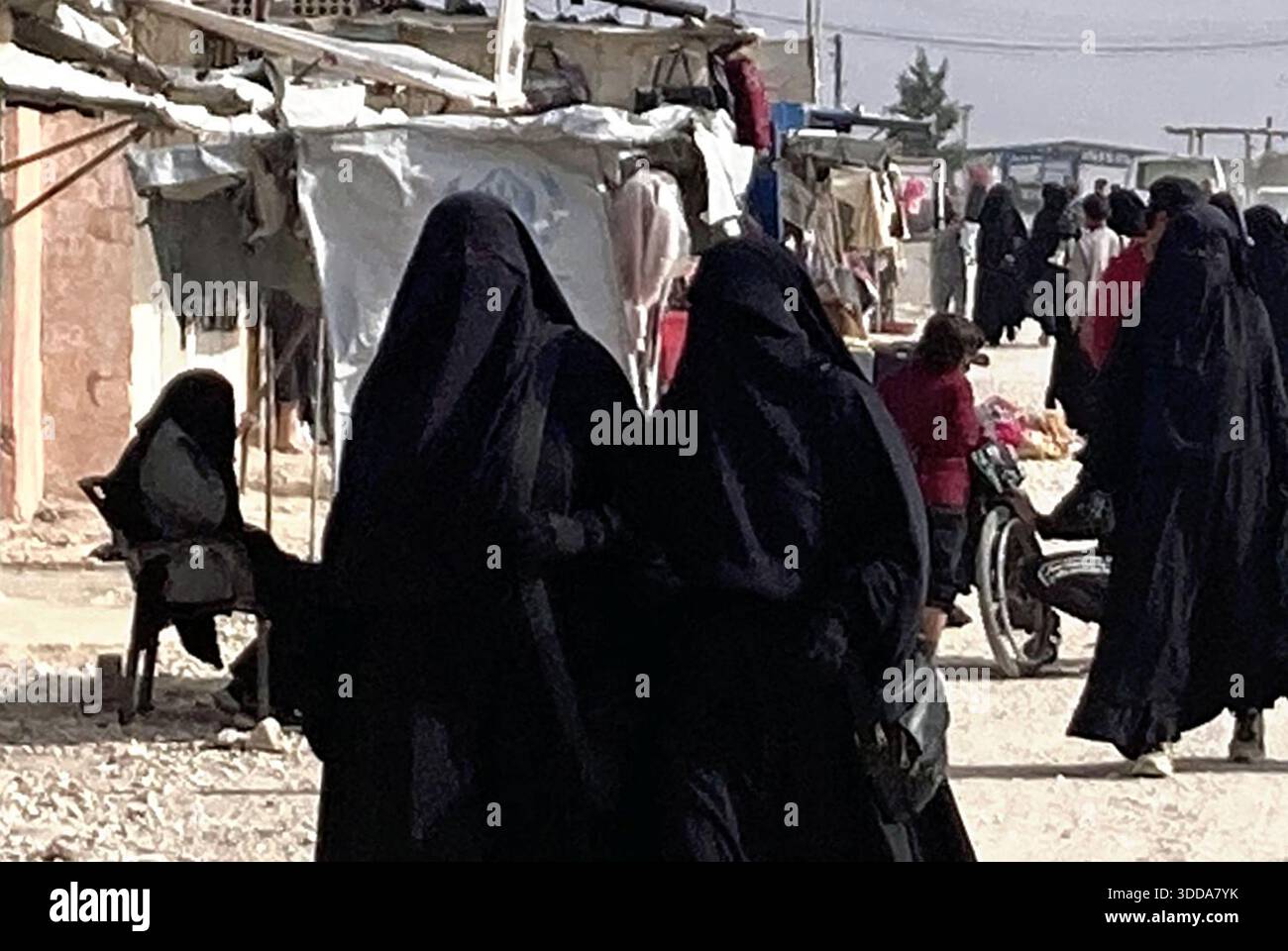 Women wearing a full-body burqa visit a market inside a camp in Al-Hol ...