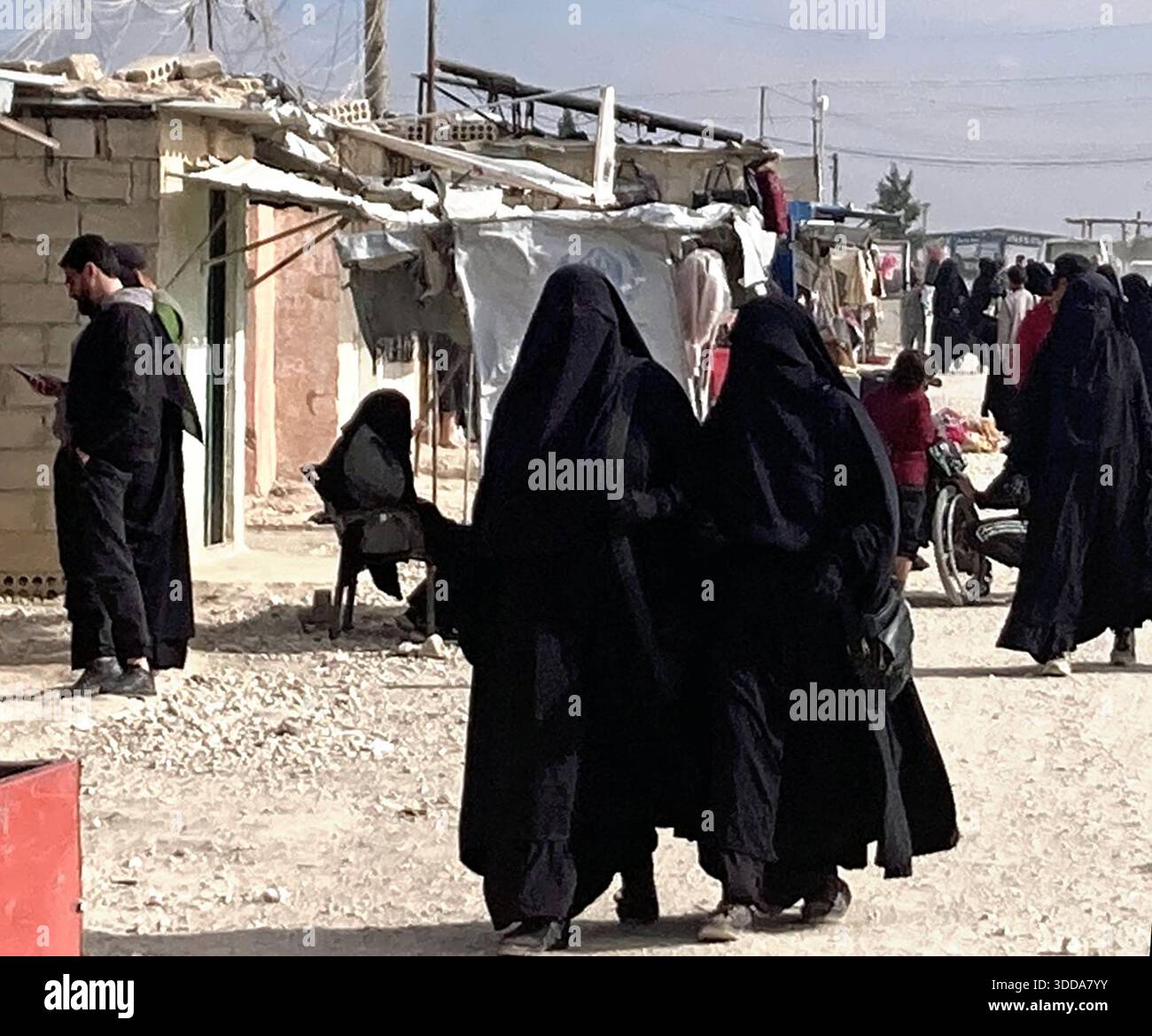 Women wearing a full-body burqa visit a market inside a camp in Al-Hol ...