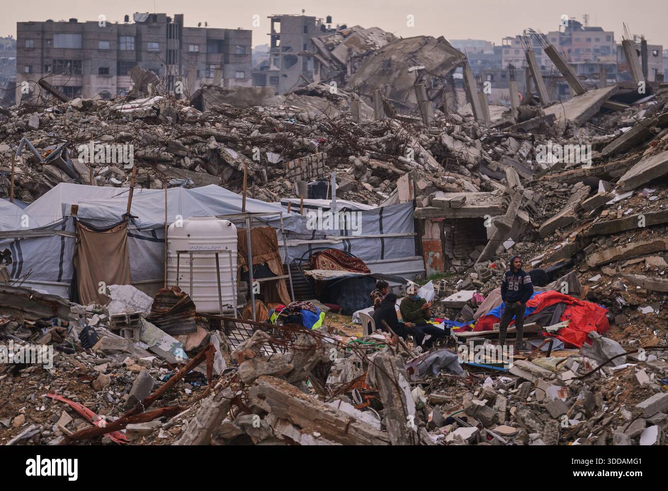 Palestinians stand next to a tent set up on the rubble of buildings ...