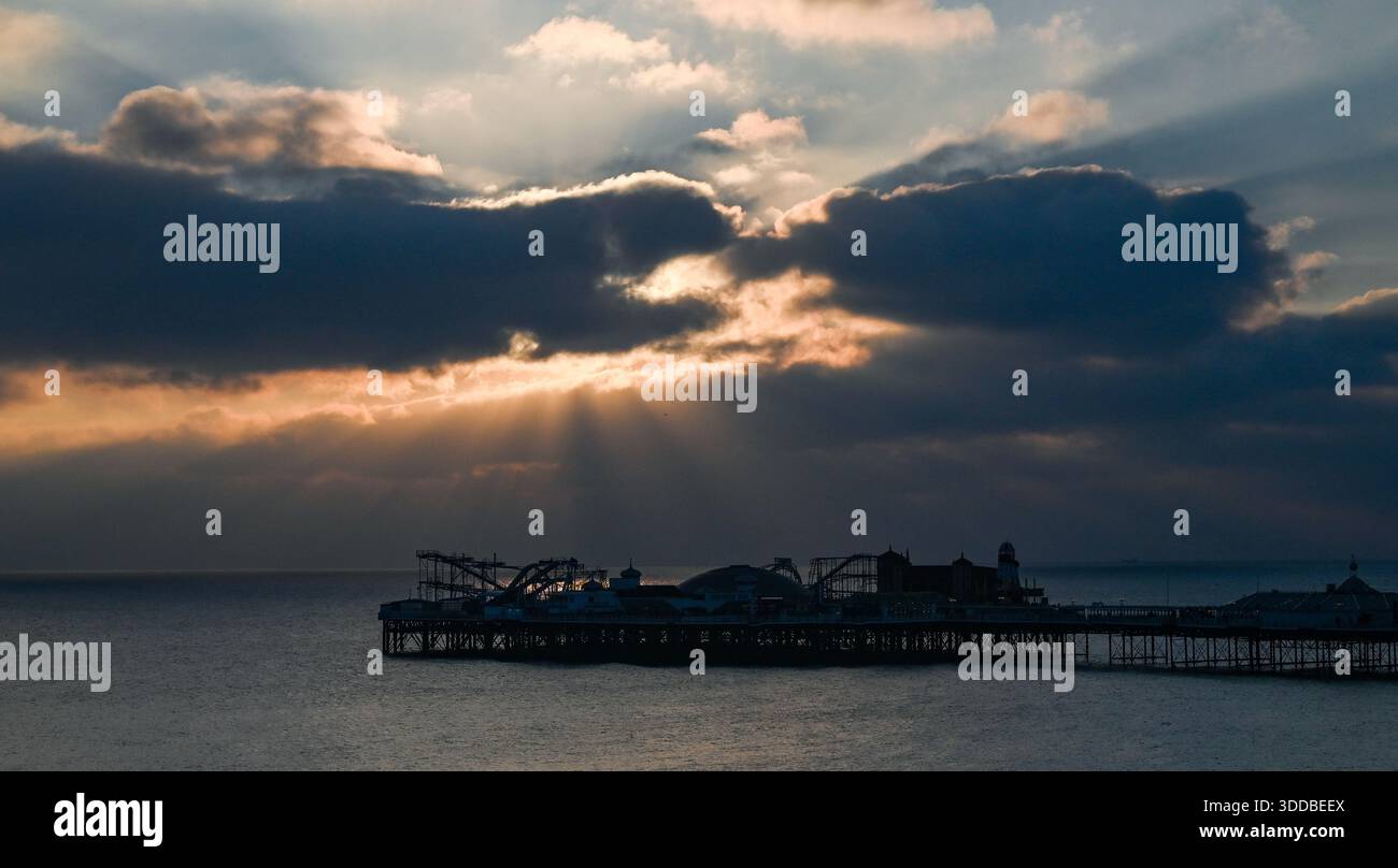 A dark moody sky with shafts of sunlight above Brighton Palace Pier ...