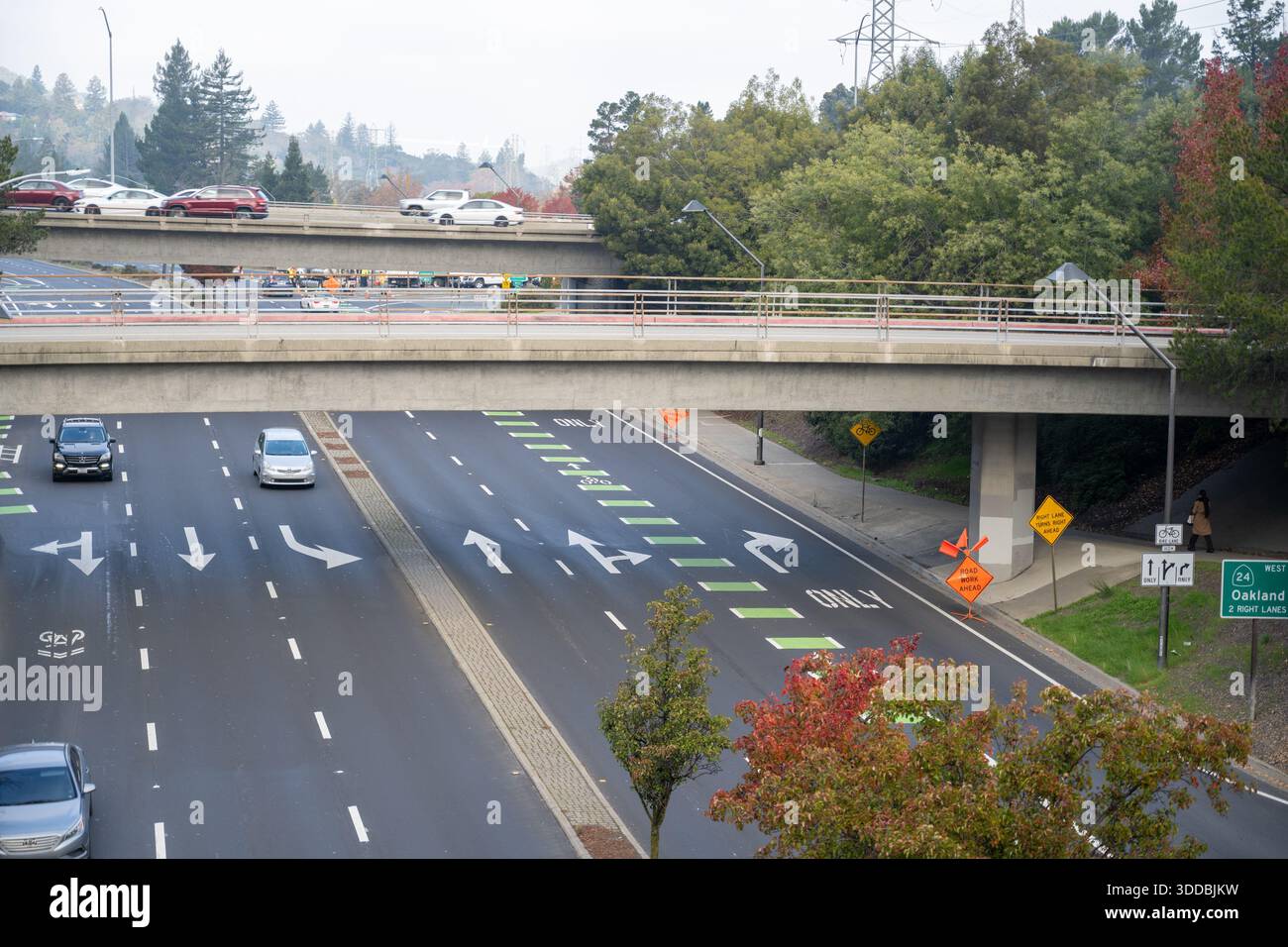 Multi-lane roadway with bike lane markings and overpass on an overcast ...