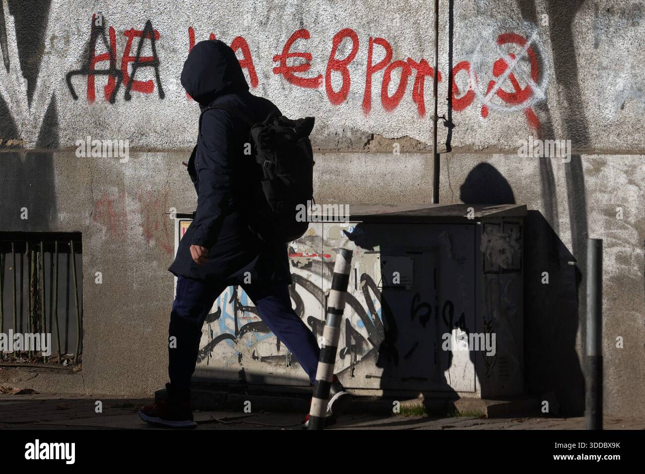 A woman passes by a graffiti reading "No to the euro" altered to "Yes ...