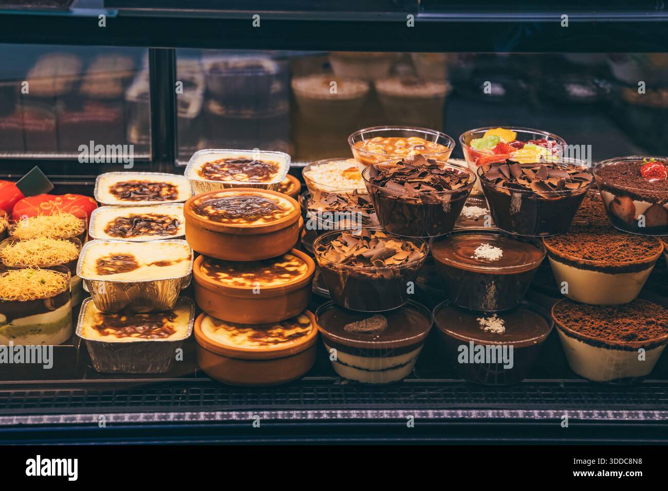 Assorted layered desserts displayed in a refrigerated showcase inside a ...
