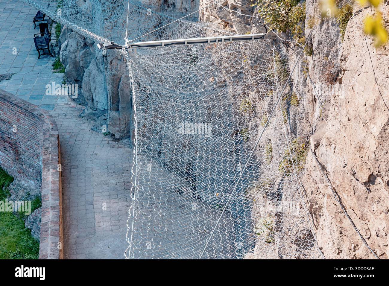 Rockfall netting installed along a stone cliff providing landslide ...