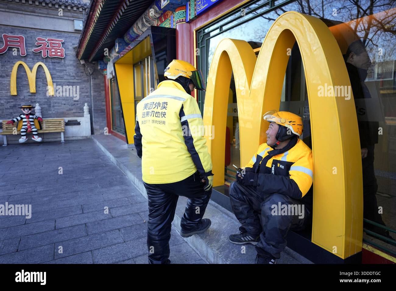 Delivery staff wait outside a McDonald's outlet in Beijing on Dec. 23 ...
