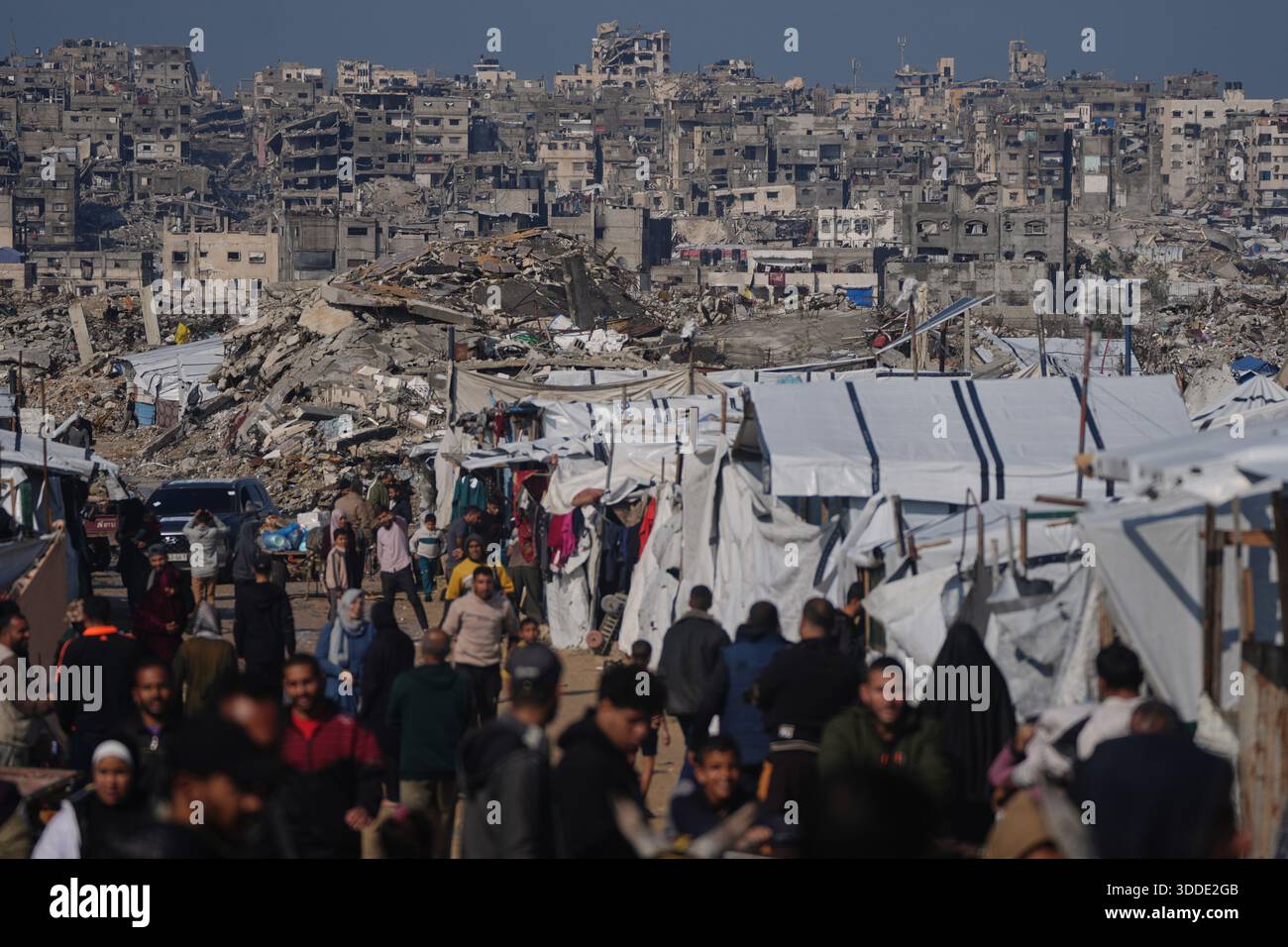 FILE - Palestinians walk along a street past a tent camp, backdropped ...