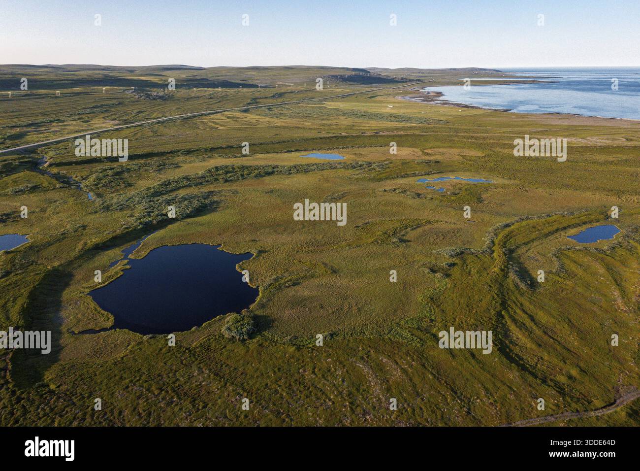 Coastal landscape on Varangerfjord with blue sky, still sea, moors and ...
