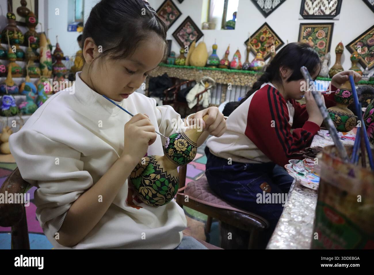 Students learn to draw patterns on gourds at a research center in Hami ...