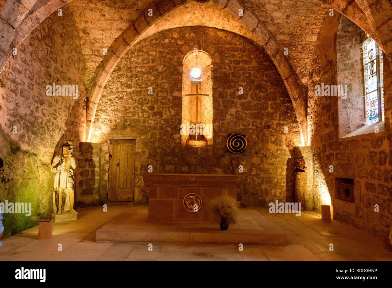Warmly lit medieval chapel interior in La Couvertoirade, featuring a ...