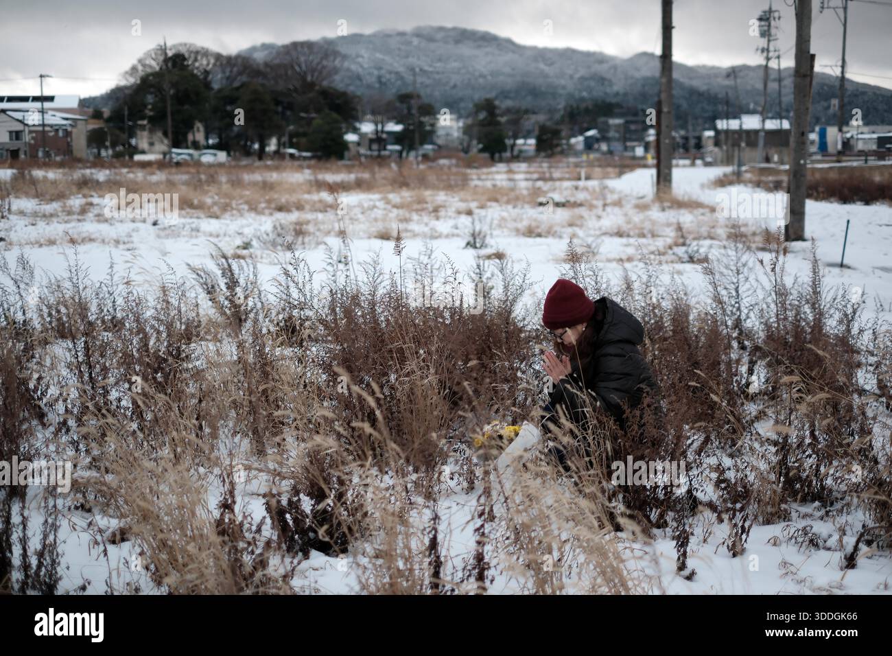 65-year-old Kumiko Hatanaka offers a bunch of flowers and prays ...