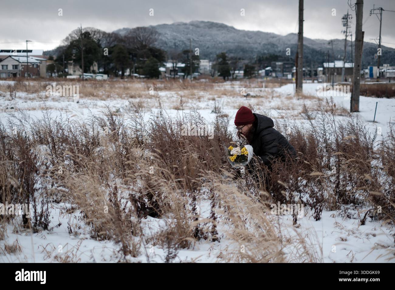 65-year-old Kumiko Hatanaka offers a bunch of flowers and prays ...
