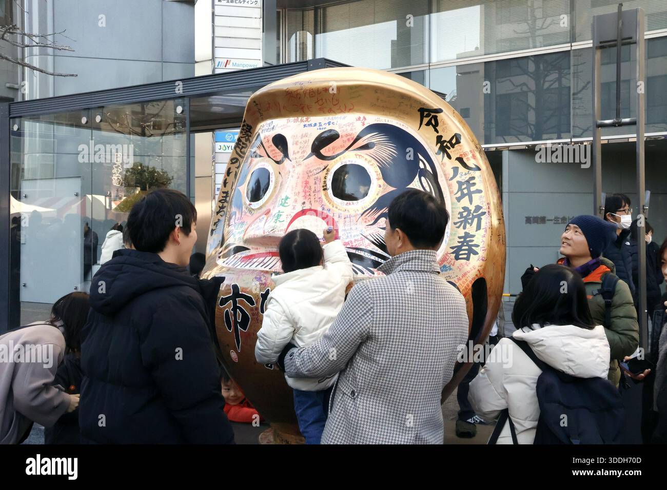 People gather around a giant "daruma" doll as a New Year market selling ...