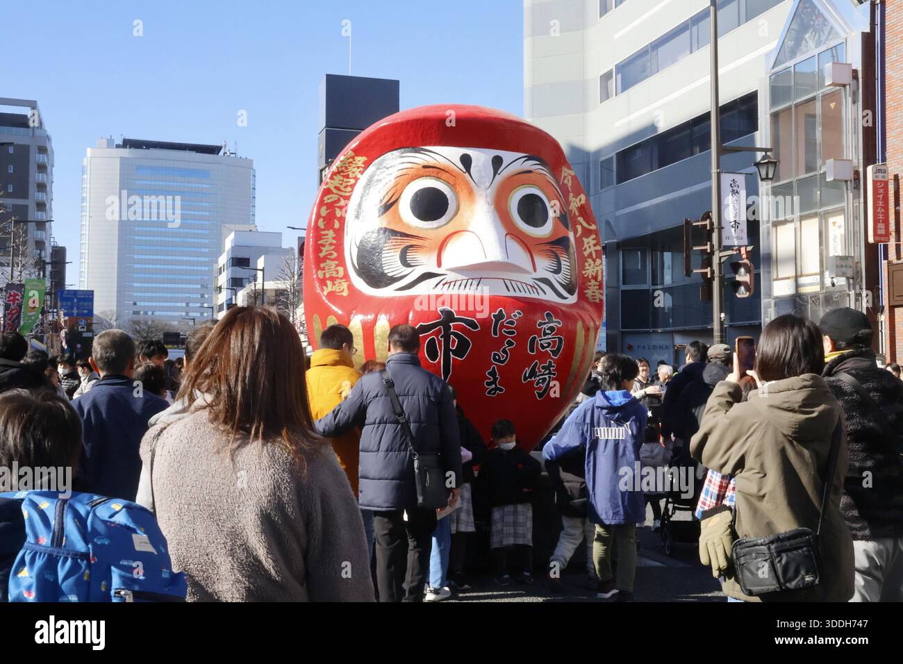 People gather around a giant "daruma" doll as a New Year market selling ...