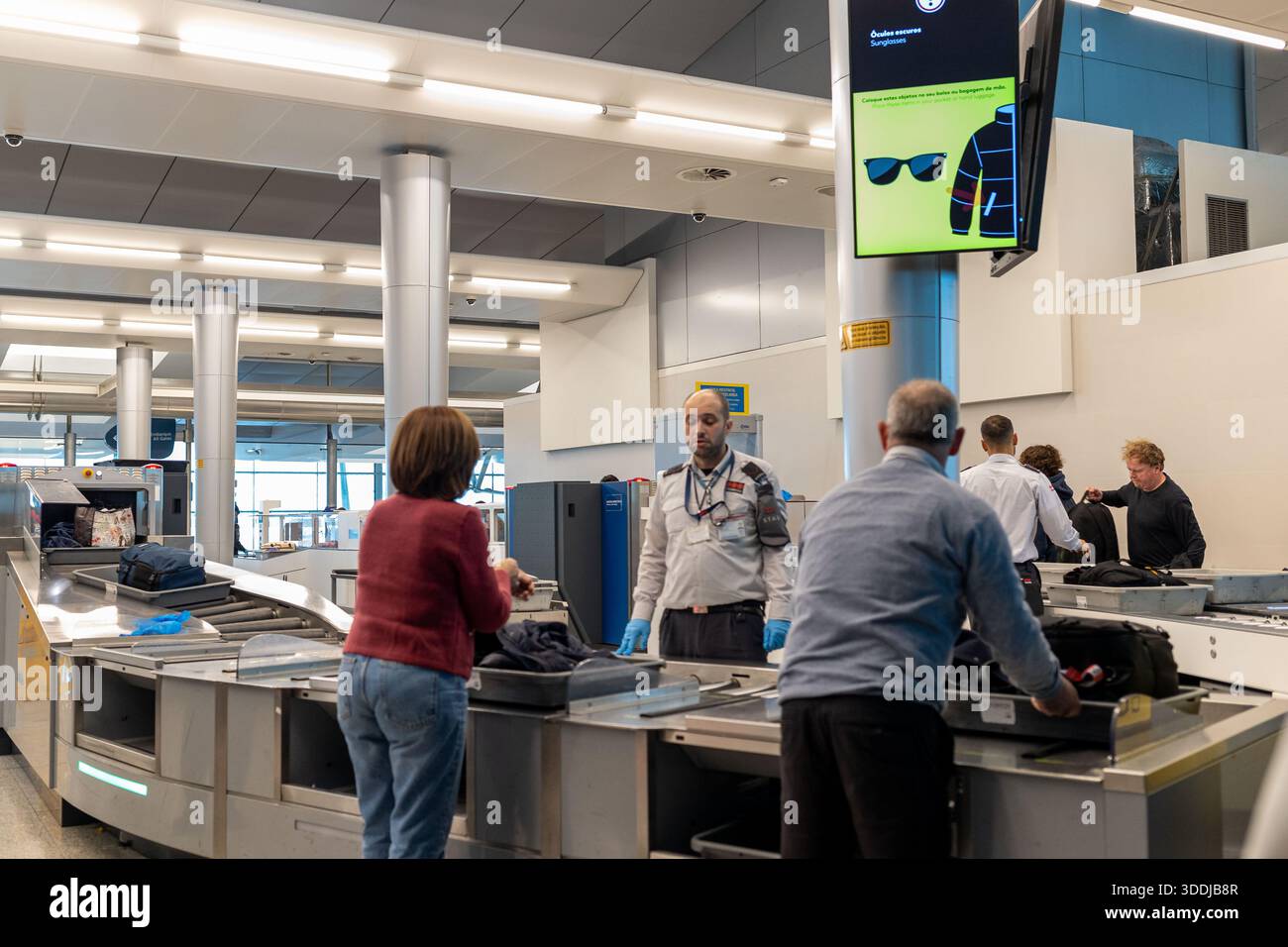 Security officers screen passengers as belongings pass through the X ...