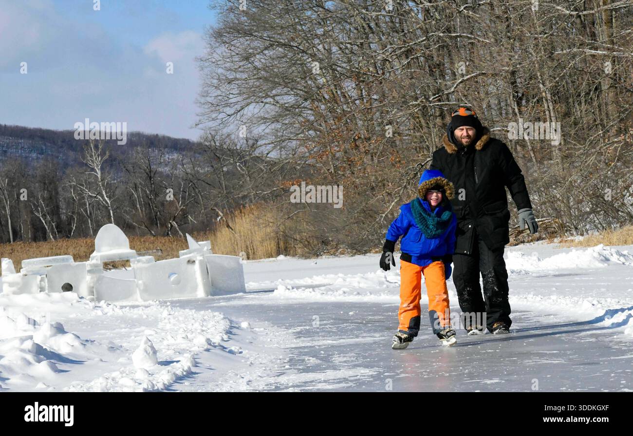 Alden Root, 7, Hinsdale, N.H., and his father, Travis, ice skate on a ...