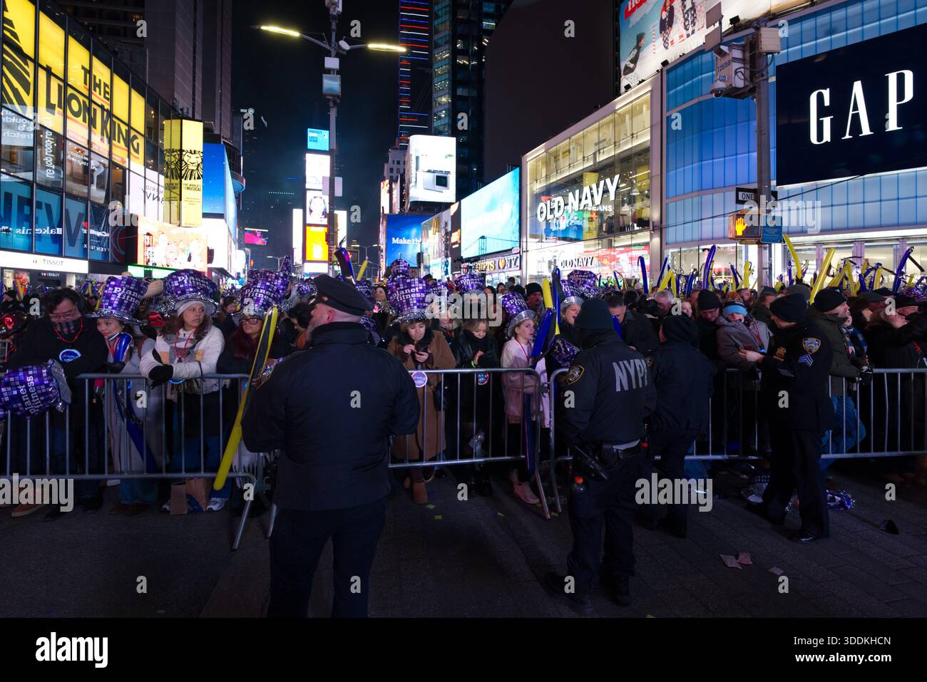 A crowd of people in New York City at night, wearing party hats and ...