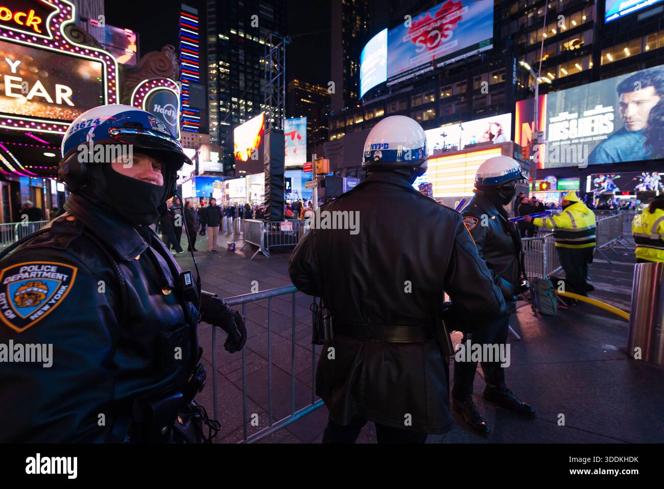 Two NYPD officers in uniform stand guard in Times Square at night ...