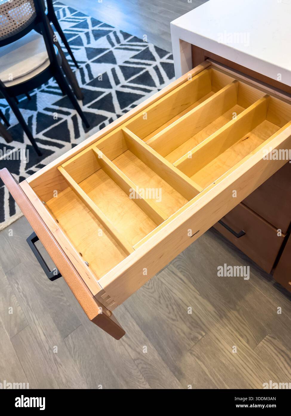 An angled view of a wooden kitchen island drawer pulled out, showing ...