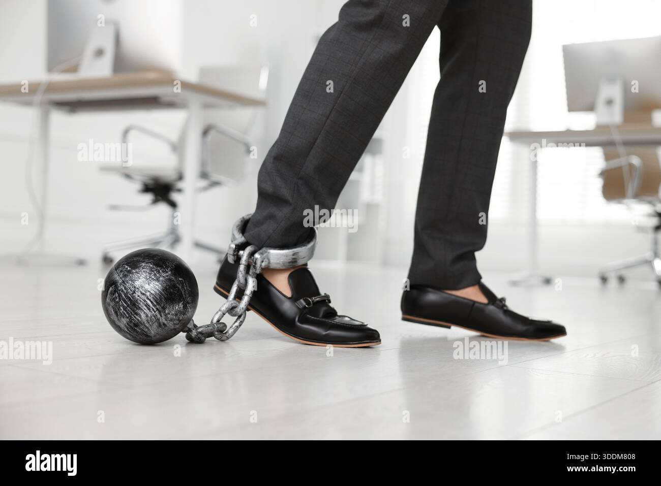 Businessman with metal ball and chain on his leg in office, closeup ...