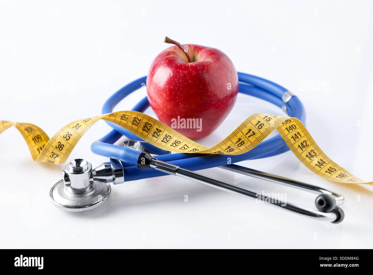 Ripe apple, stethoscope and measuring tape on white table, closeup ...